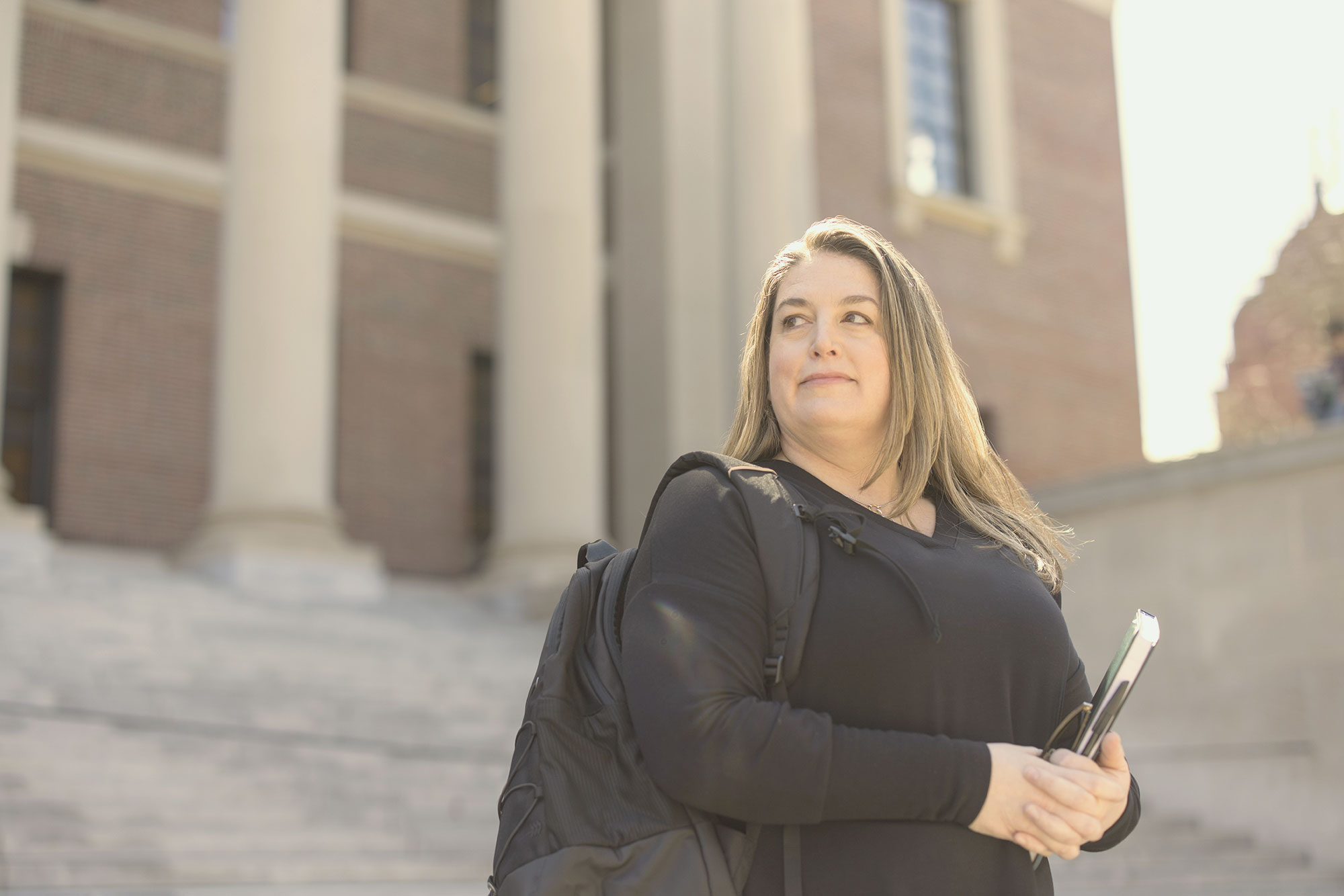 A woman looks over her left shoulder while walking down steps.